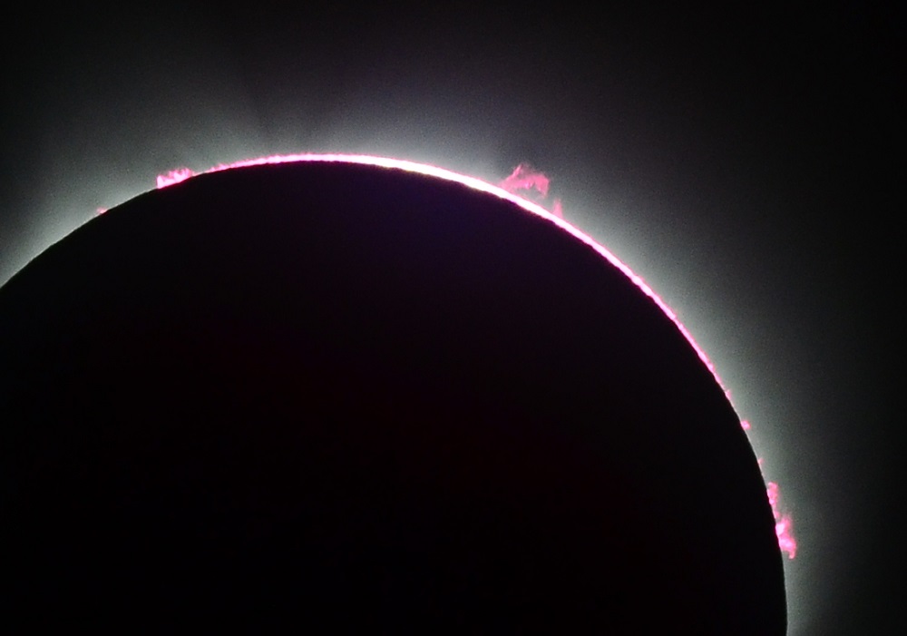 Solar prominences on limb of sun, at end of totality. - Sky & Telescope